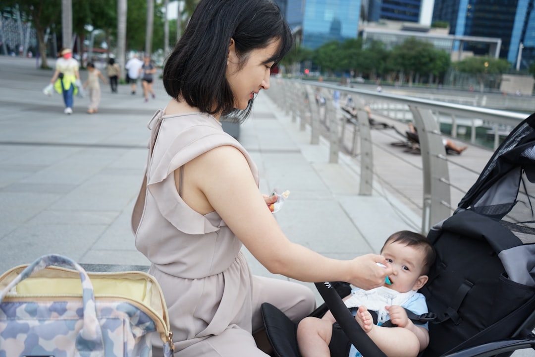 woman in beige sleeveless shirt carrying baby in white shirt